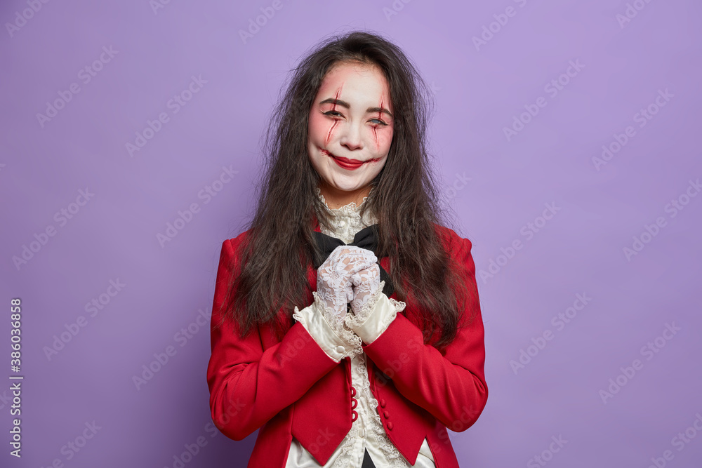 Spooky happy woman has image of zombie keeps hands together wears ghost ...