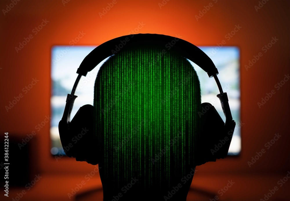 Young gamer with headphones playing computer game on glowing screen in ...