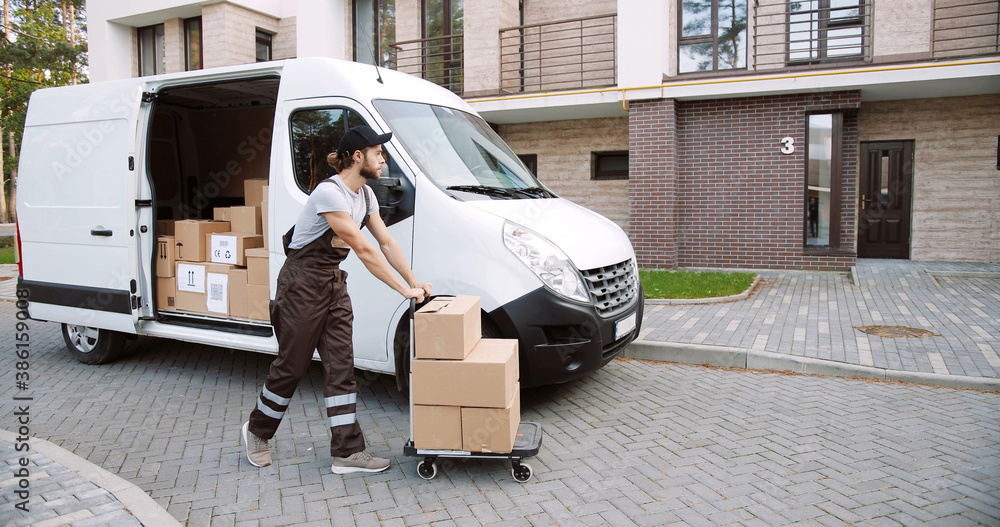 Delivery man pushes hand truck trolley full of cardboard. Stock Photo ...