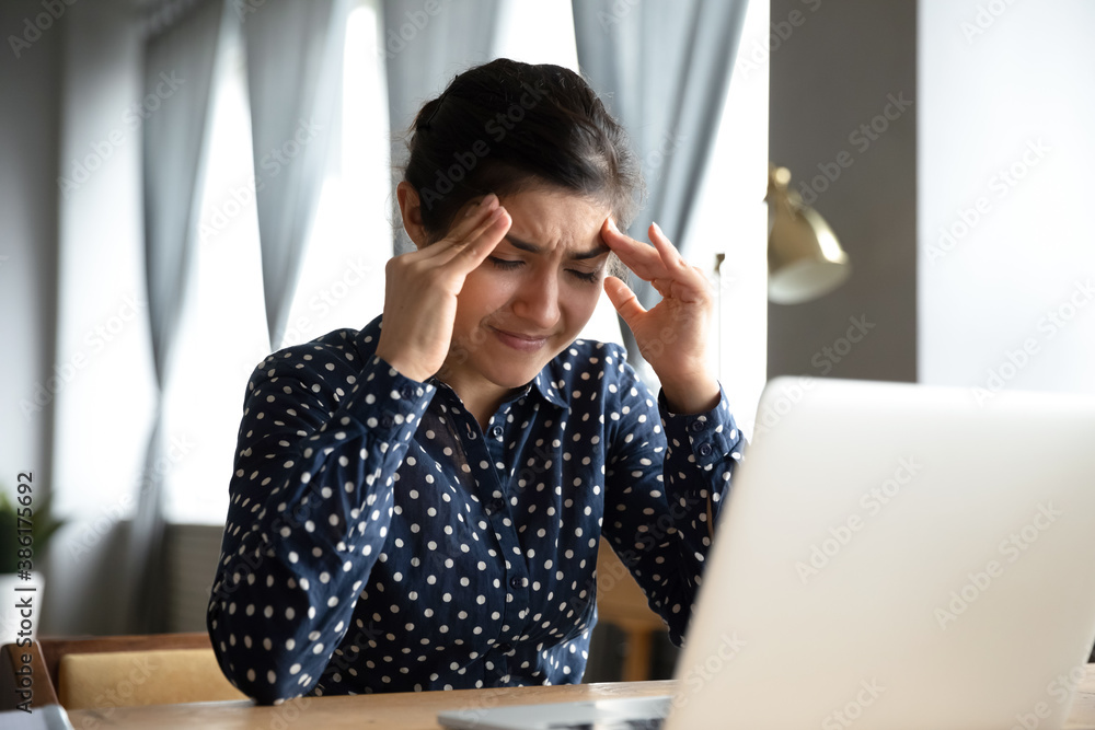 Indian woman sit at desk closed eyes rub temples forehead try to ...
