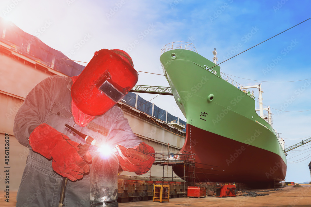 Male in face mask welds with argon-arc welding, Worker welding ship ...