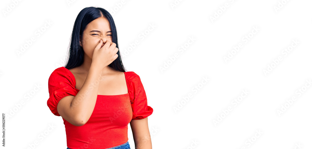 Young beautiful asian girl wearing casual clothes smelling something ...