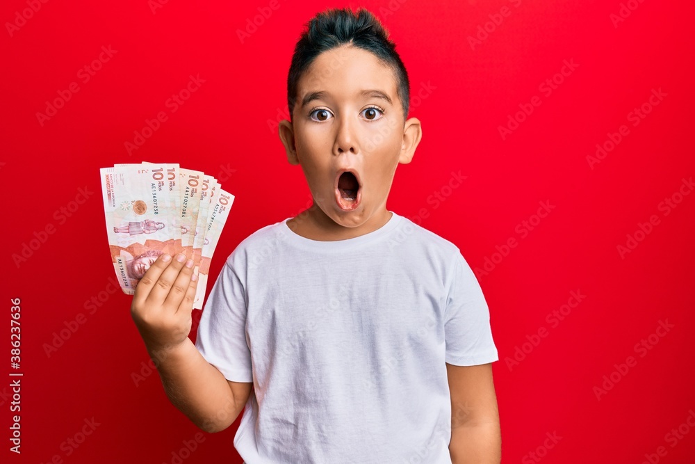 Little boy hispanic kid holding 10 colombian pesos banknotes scared and ...