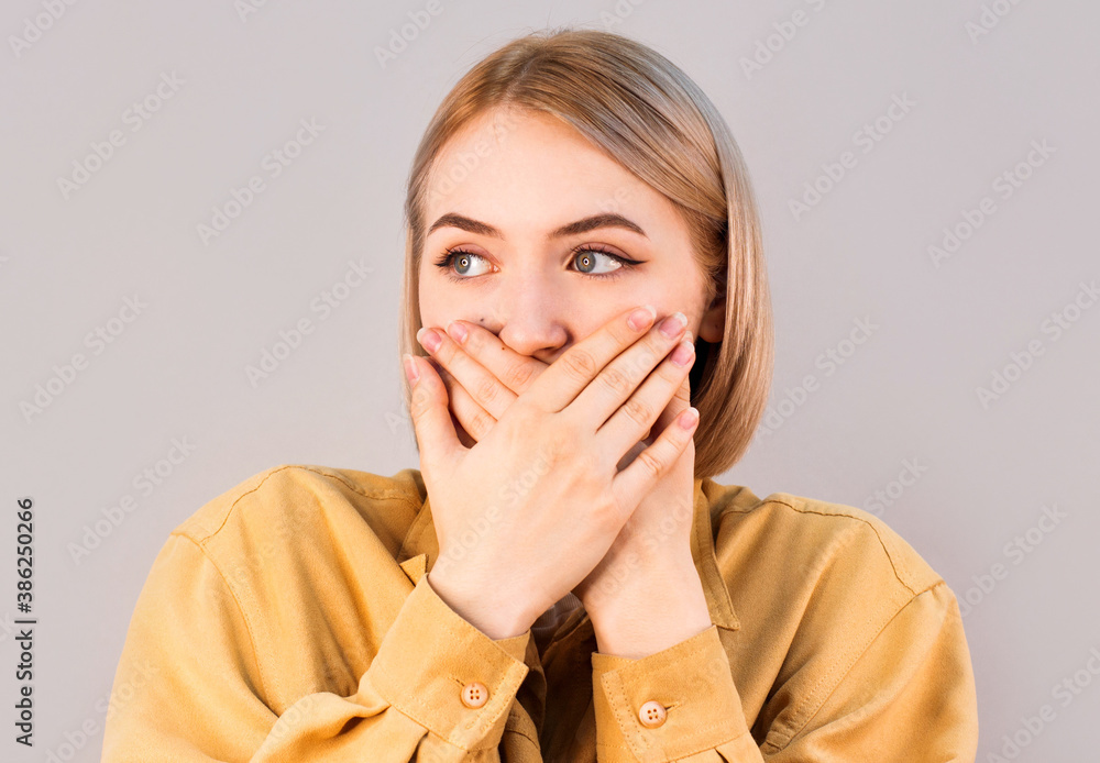 Keep silence. Scared woman covering mouth with hands while posing to ...