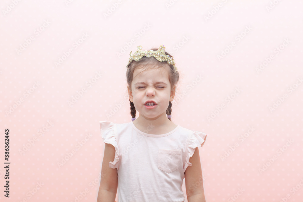 Moody little girl wearing princess tiara feeling angry and unsatisfied ...