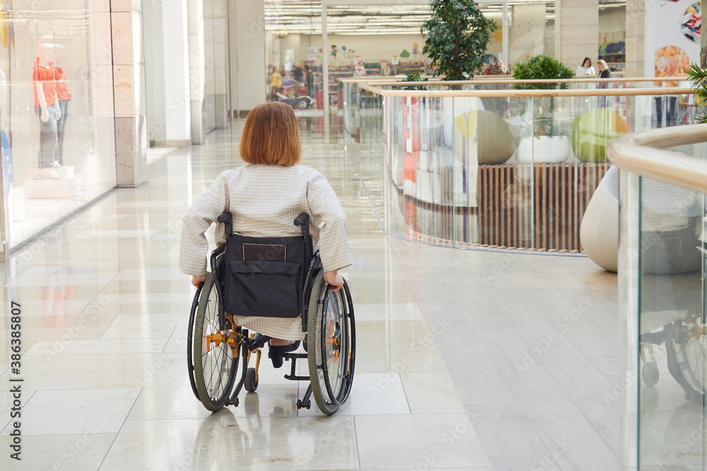 A disabled woman shopper moves in a wheelchair along the shopping ...