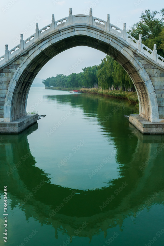 a stone bridge above a calm lake in the Summer Palace, Beijing, China ...
