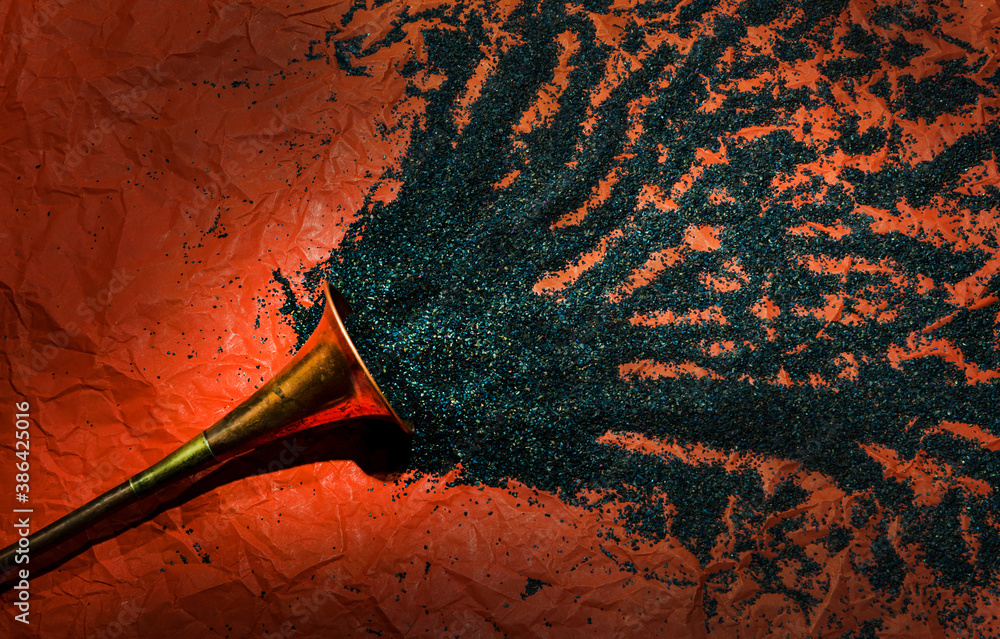 Visual music, black powder scattering from a tube on an orange ...