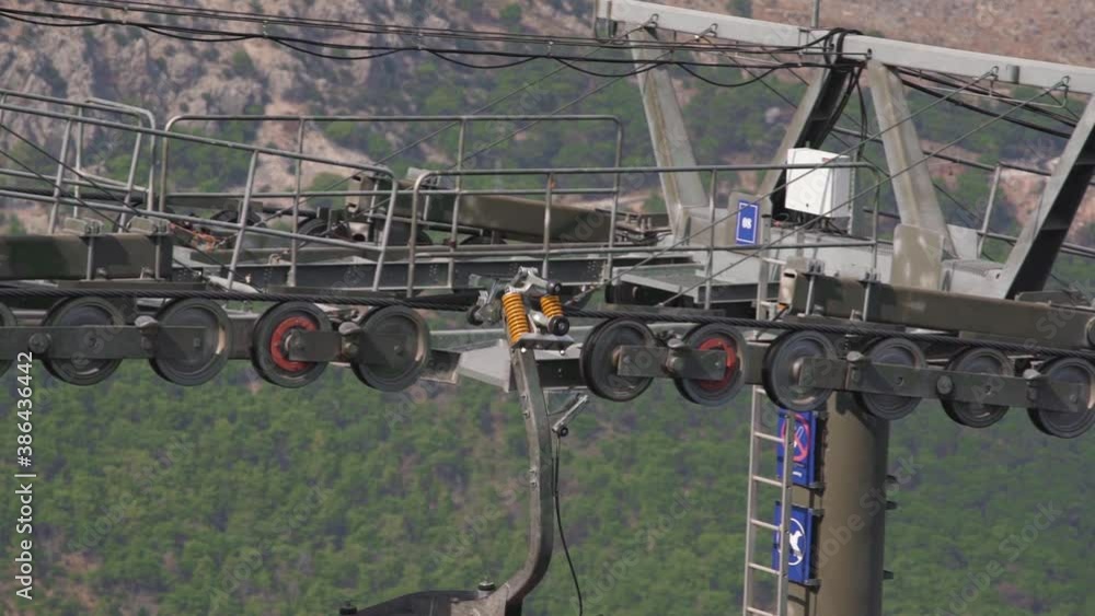 Mechanism of contemporary cable-way with cabin moving past grey metal ...