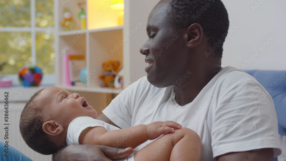 African father calming crying baby in his arms before going to bed ...