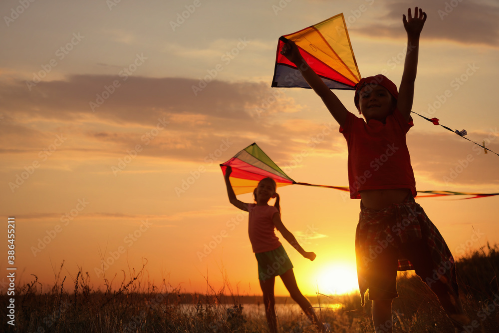 Cute little children playing with kites outdoors at sunset. Spending ...
