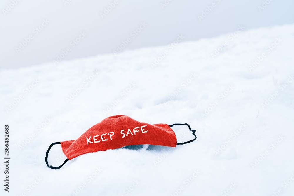 Red medical face mask on top of a snowy ground. Concept of covid-19 ...