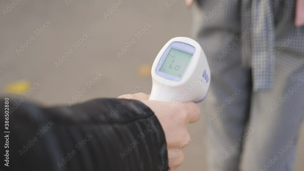 Female security guard, using digital medical electronic thermometer ...