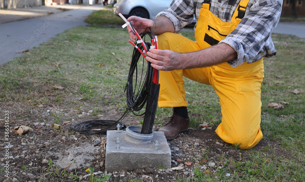 Worker installing optic fiber cables for internet and telephone, power ...