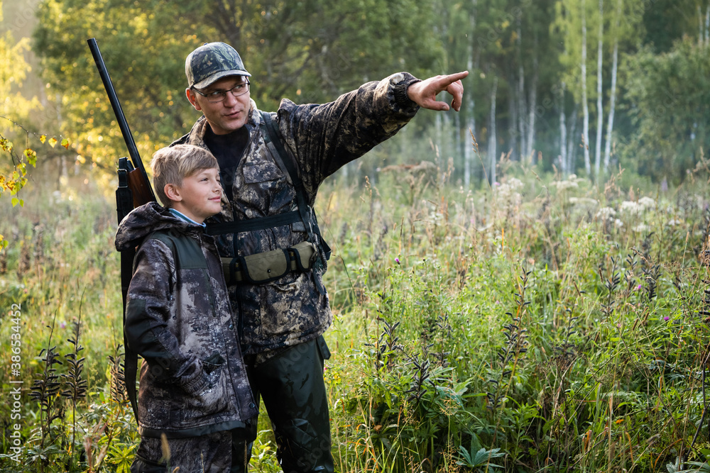 Father's day. Father with gun showing something to son while hunting on ...