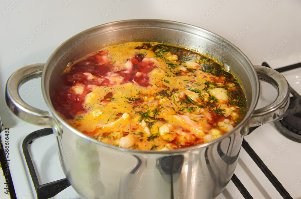 Foto de Metal saucepan with boiling vegetable soup on a gas stove ...