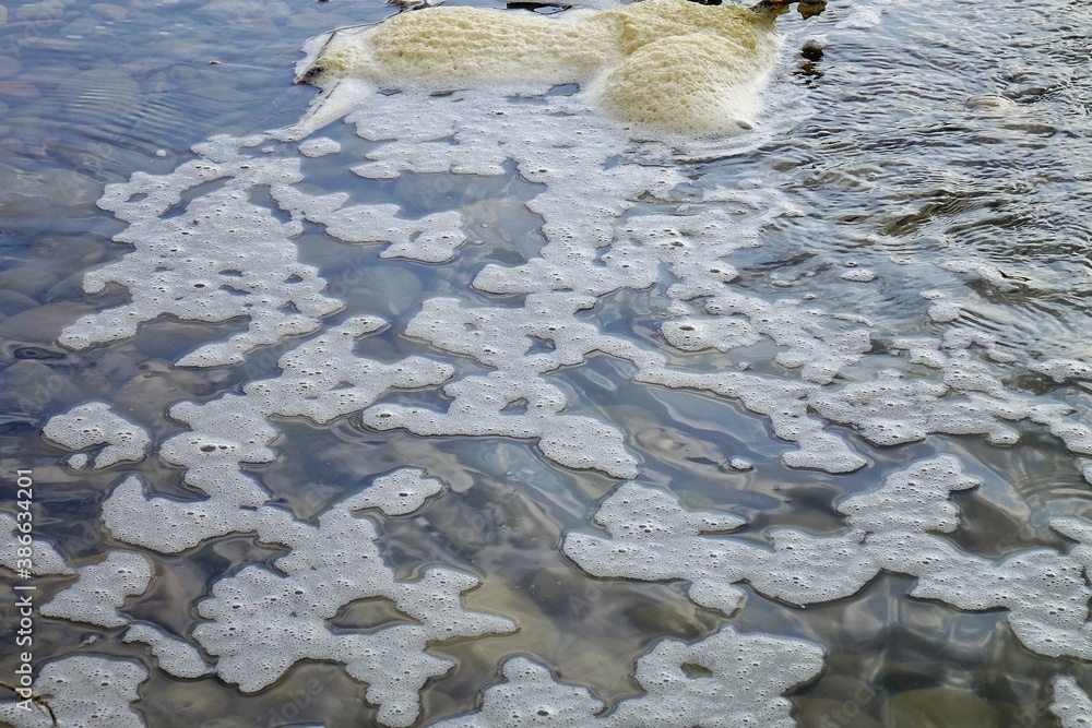 Foam flakes on the water surface of a mountain river. Environmental ...