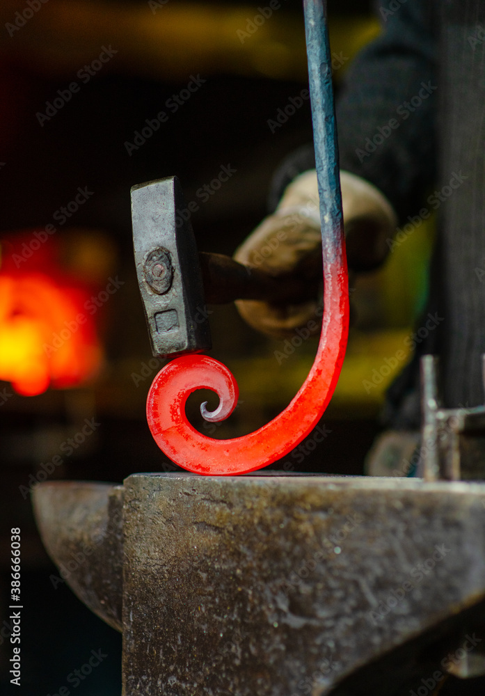 The blacksmith twists the spiral with a sledgehammer, placing a red-hot ...