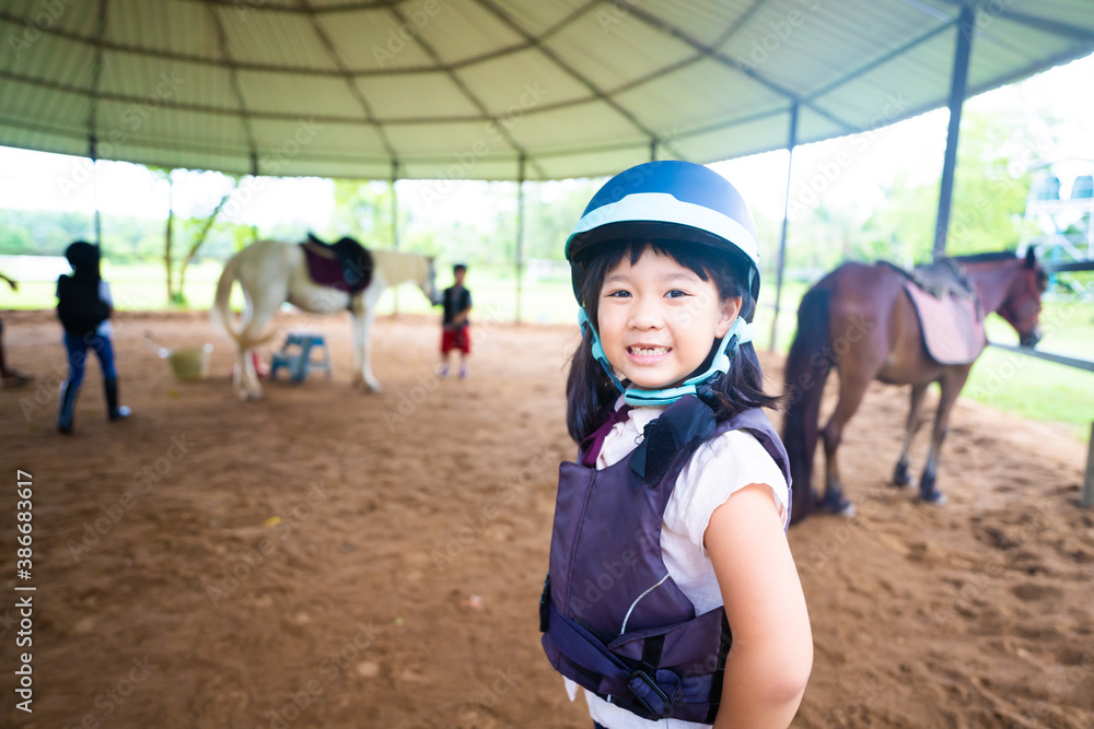 Horse rider.Back view Kids learn to ride a horse.Happy asian kid girl ...