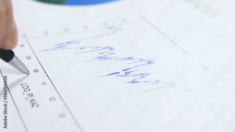 Man writing on a paper with graph closeup. Holding black pen on a blue ...