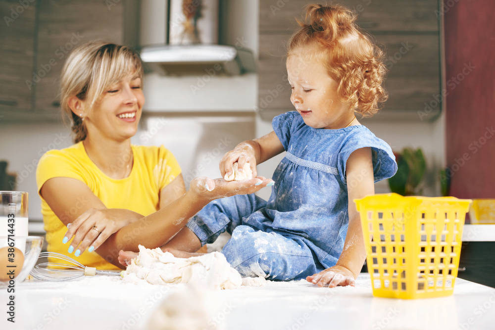 A young girl smiles and holds the dough in her hand and gives it to her ...