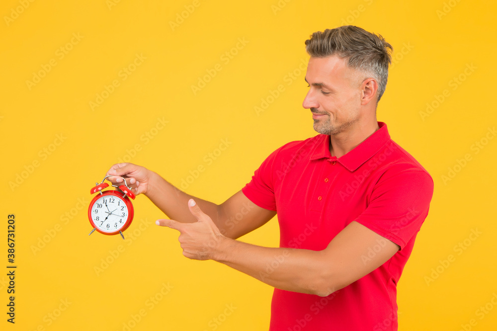 Look at clock. Handsome man point finger at alarm clock. Check current ...