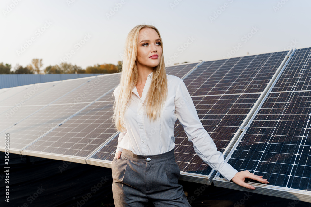 Blonde model with solar panels stands in row on the ground. Girl ...