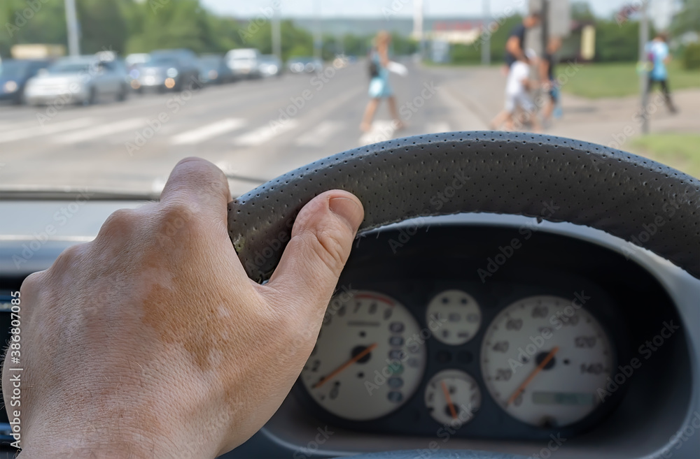 the driver's hand on the steering wheel of the car, which is standing ...
