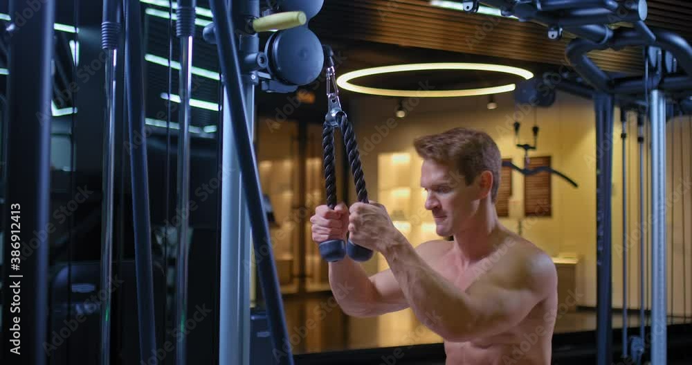 Young athlete takes a rope on a strength machine and begins to swing ...