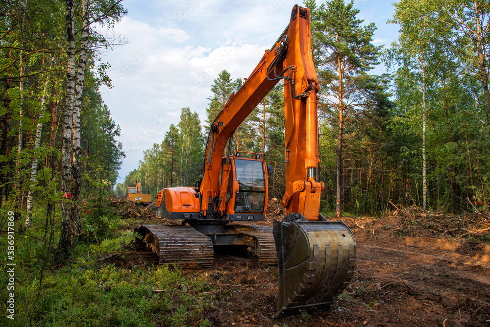 Excavator clearing forest for new development. Orange Backhoe modified ...