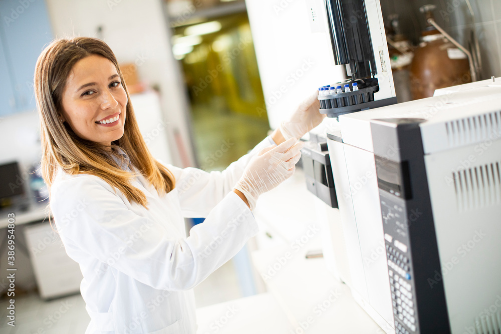 Female scientist in a white lab coat putting vial with a sample for an ...