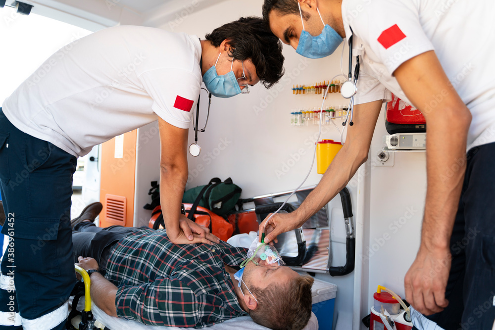 Male first aid workers giving CPR to someone who has had a heart attack ...
