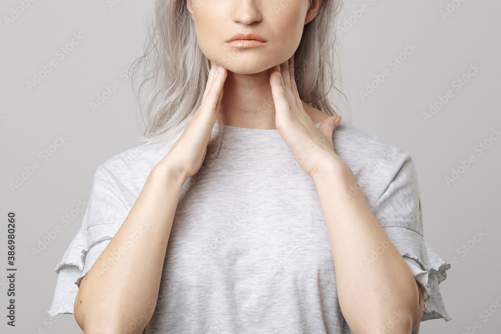 Female checking thyroid gland by herself. Close up of woman in white t ...