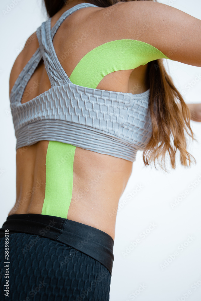 Back view. Woman athlete with kinesio tape on her back. Kinesio taping ...