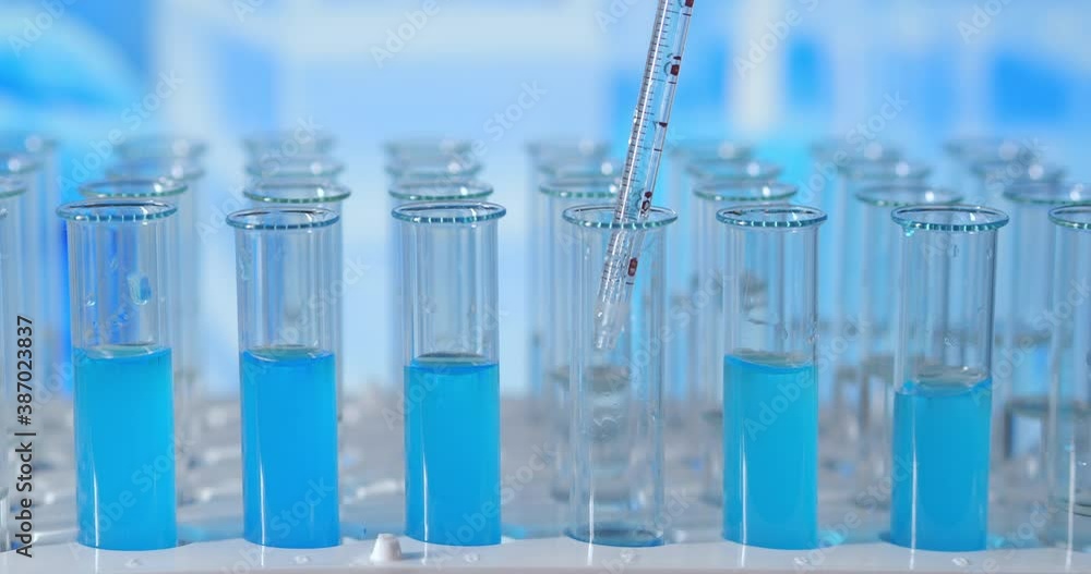 Scientist injecting chemicals into test tubes. Test tube of colored ...