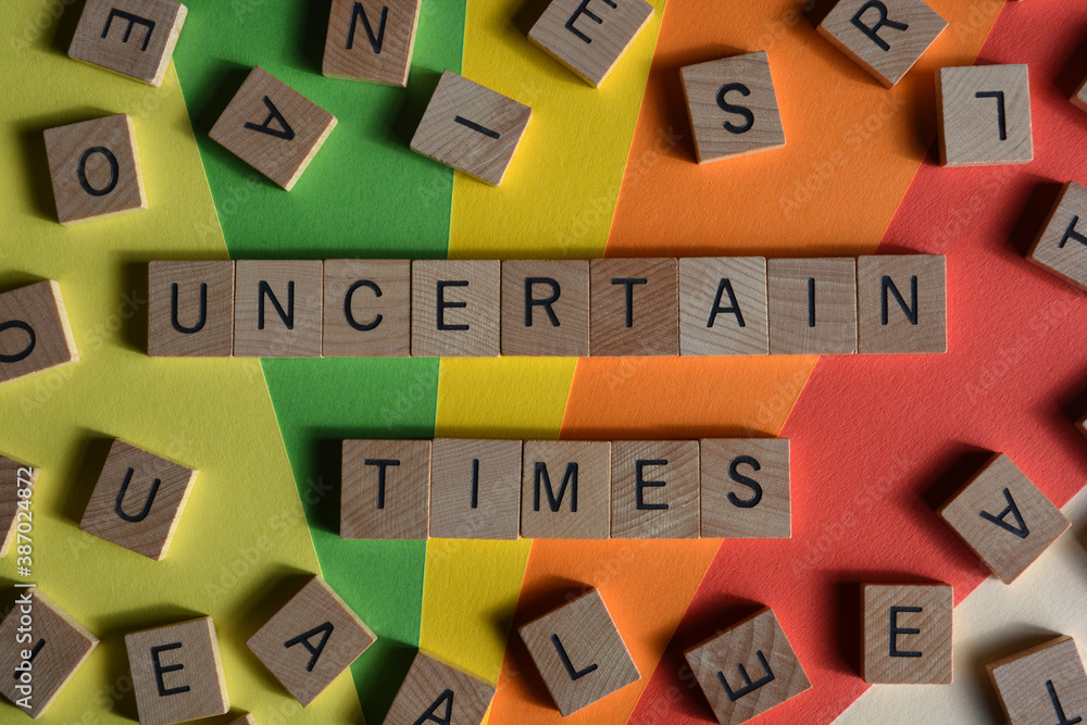Uncertain Times, words in wooden letters surrounded by random alphabet ...