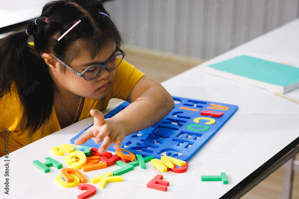 Girl with Down's syndrome play alphabet puzzle toy. Stock Photo | Adobe ...