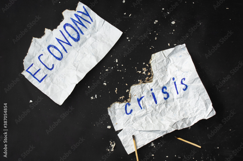 Inscription "Economy crisis" on two crumpled burnt paper sheets against ...