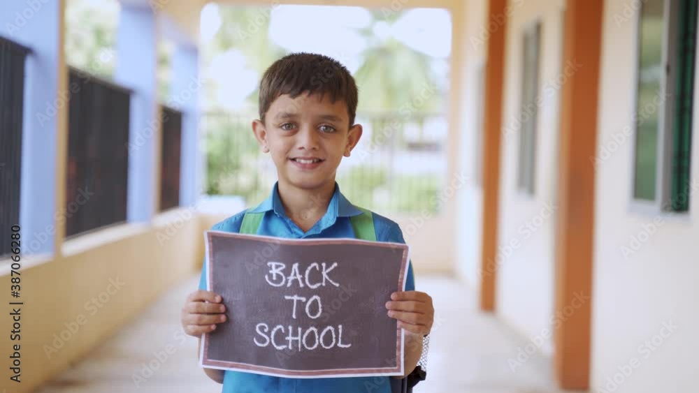 Young kid coming front by looking camera and showing by back to school ...