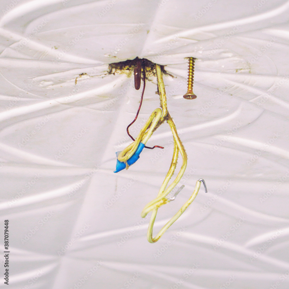 Dangerous bad wiring which hangs on the ceiling Stock Photo | Adobe Stock