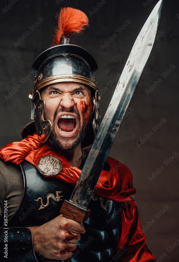 Mad roman soldier with blood on his face and dark armour screaming and ...