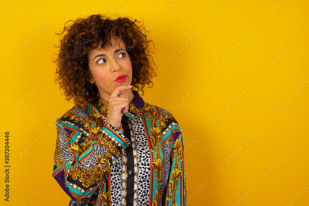 Shot of contemplative thoughtful Young woman keeps hand under chin ...
