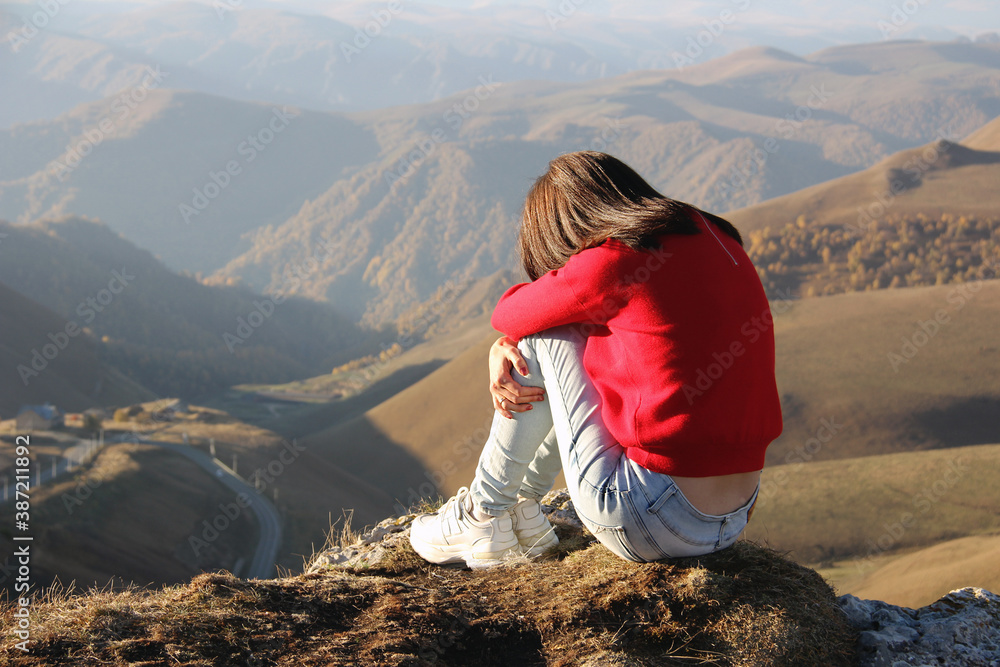 Image of a depressed and upset young woman sitting on the edge of an ...