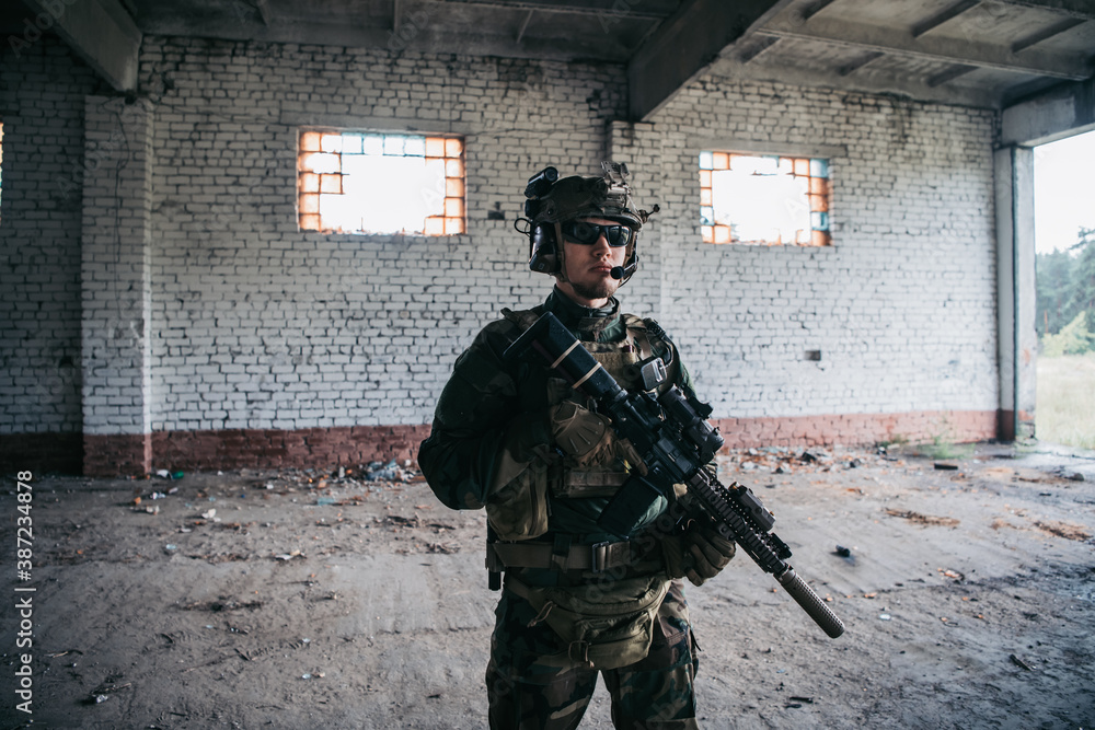 Military man with assault rifle standing inside building, he is ready ...