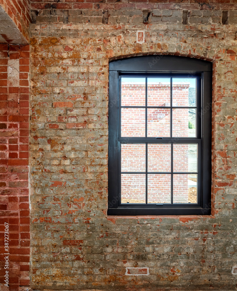 old red brick wall with window with curved brick arch, shot from inside ...