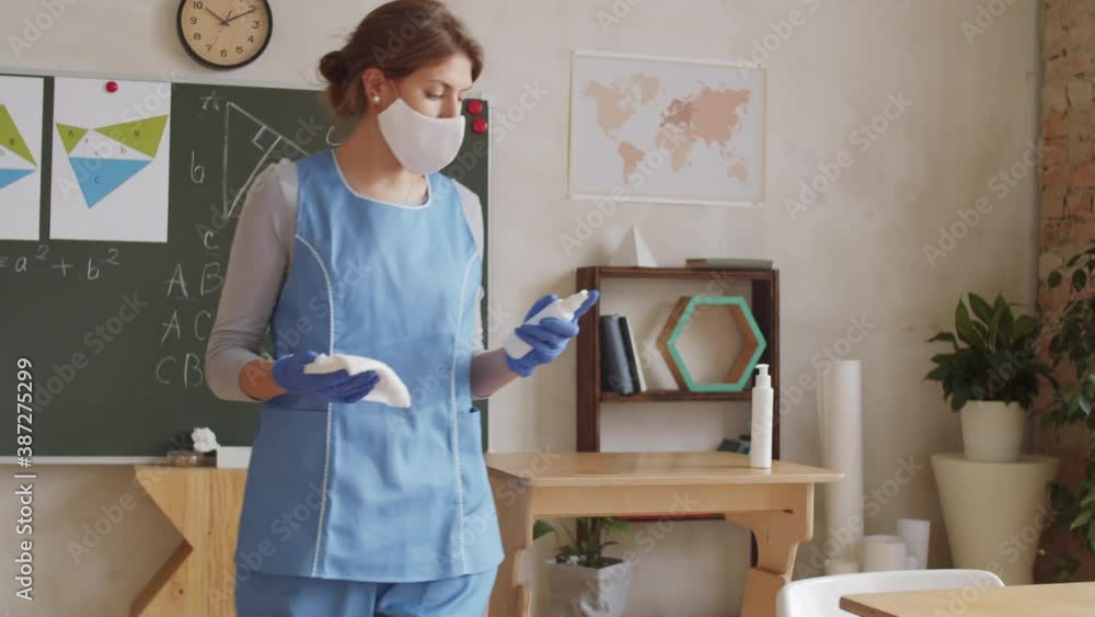 Young caucasian janitress in uniform, protective mask and gloves ...