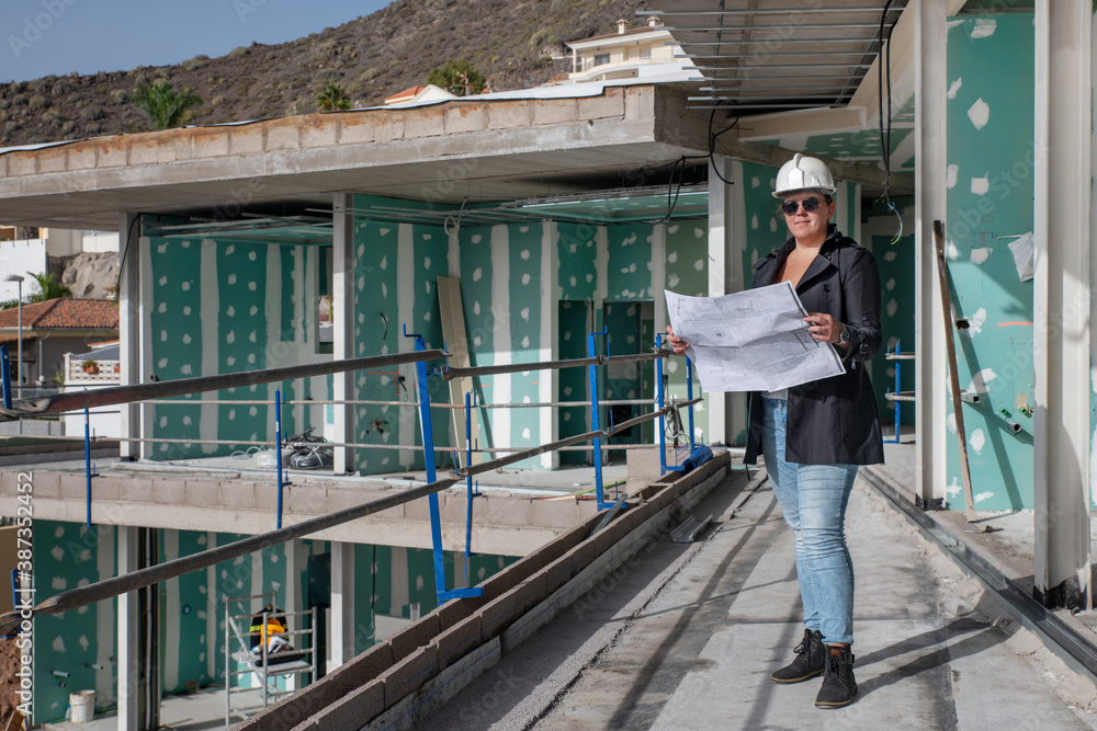Young architect wearing a safety helmet and sunglasses reading the ...
