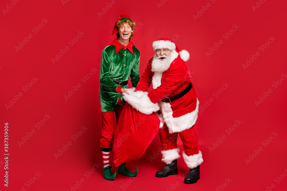 Full length photo of two men santa elf hold open big sack funny face ...