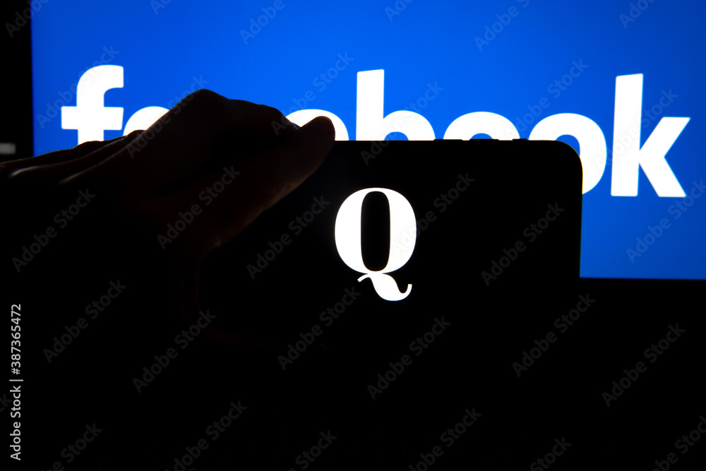 QAnon vs FACEBOOK. QAnon organization logo seen on the smartphone which ...