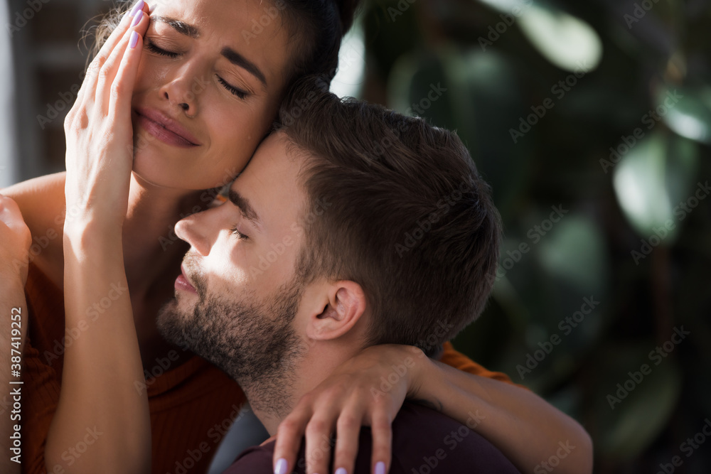 crying woman touching face while embracing beloved man at home Stock ...